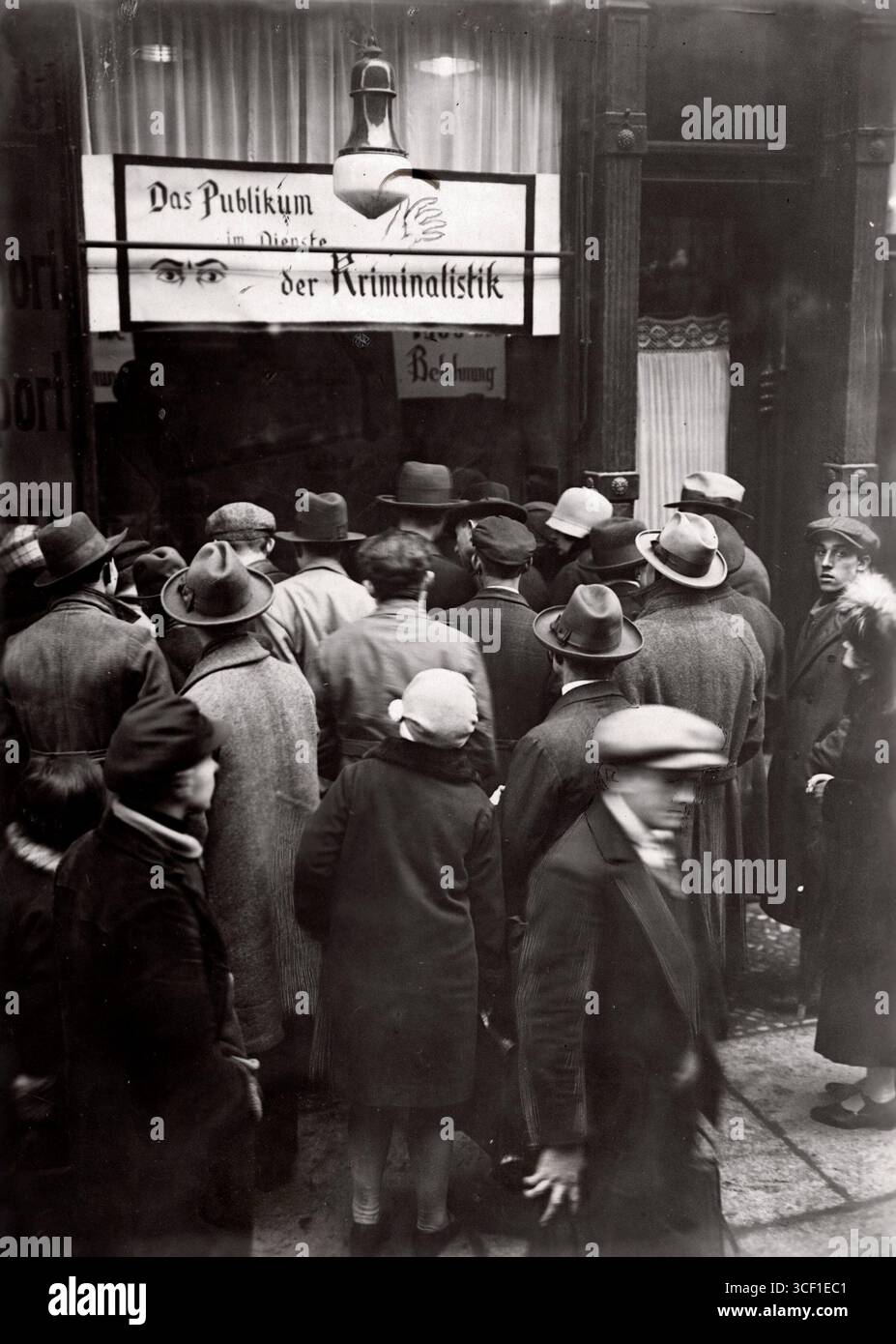 A group of people in Berlin, Germany, 1928, stands under a sign calling ...