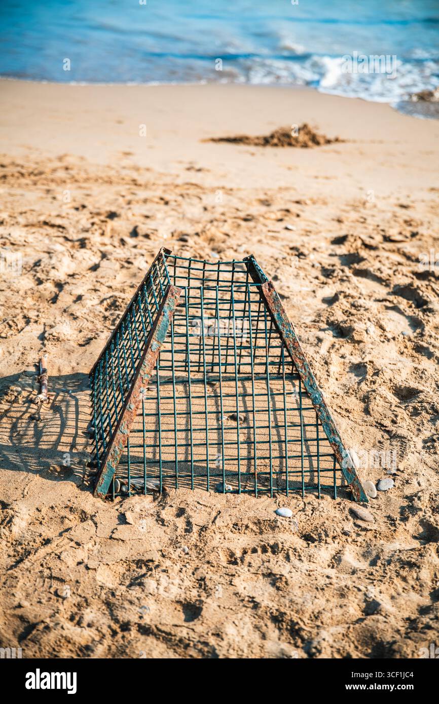 Rusty metal cage surrounding a sea turtle nest on a sandy beach ...