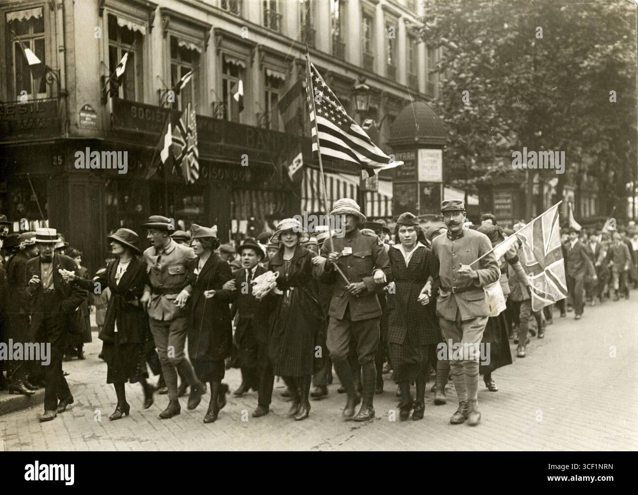 Civilians and soldiers with American flags walk arm in arm through the ...