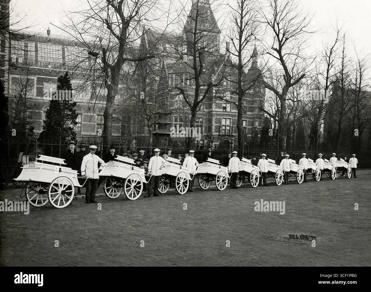 Eleven milk vendors in white jackets stand with their milk carts in ...