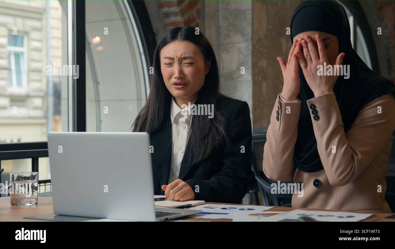Two multiethnic business women in office looking computer screen ...