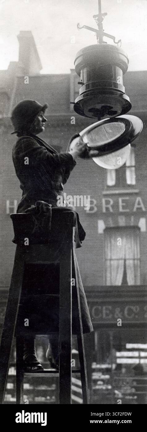 This 1915 photo shows a female lamplighter in London, performing a ...