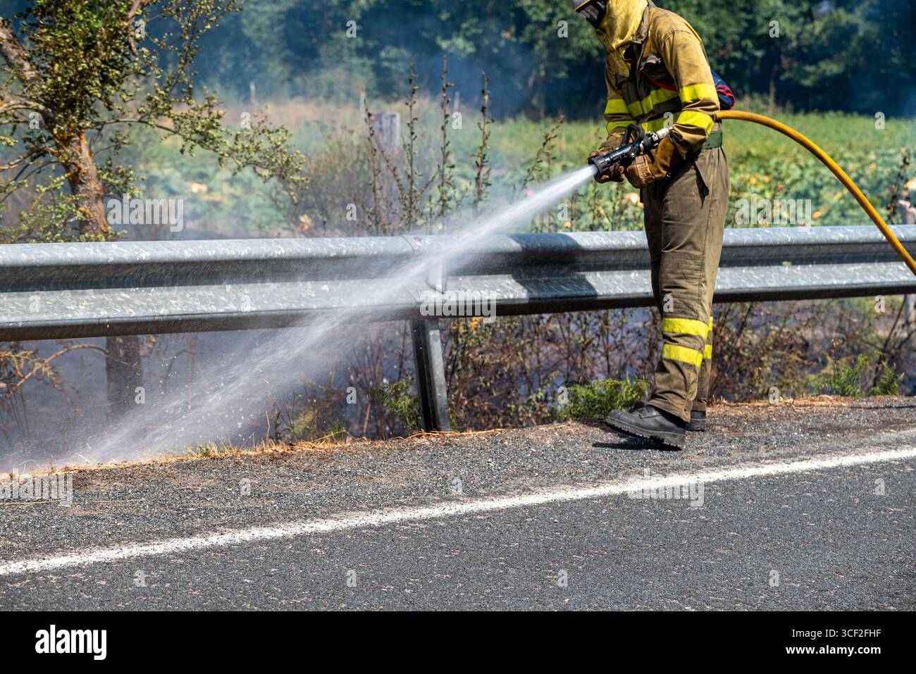 A Firefighter Spraying Water on a Roadside Fire. Concept Protecting ...