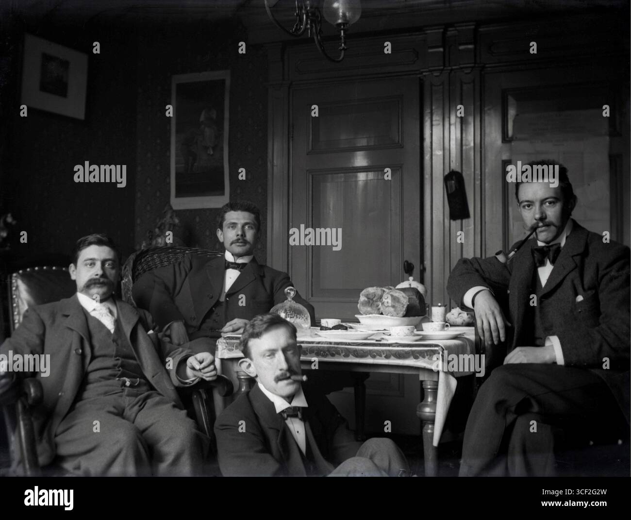 Four young men, possibly students, sit around a set table for a meal ...