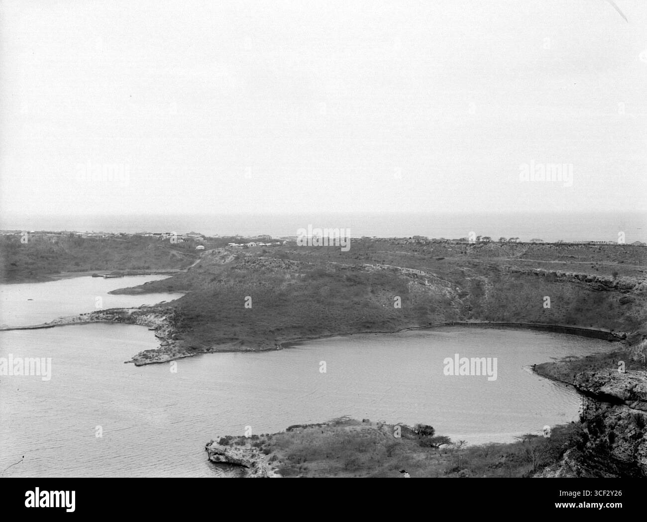 A 1930-1950 negative showing a narrow, built-up peninsula with calm ...