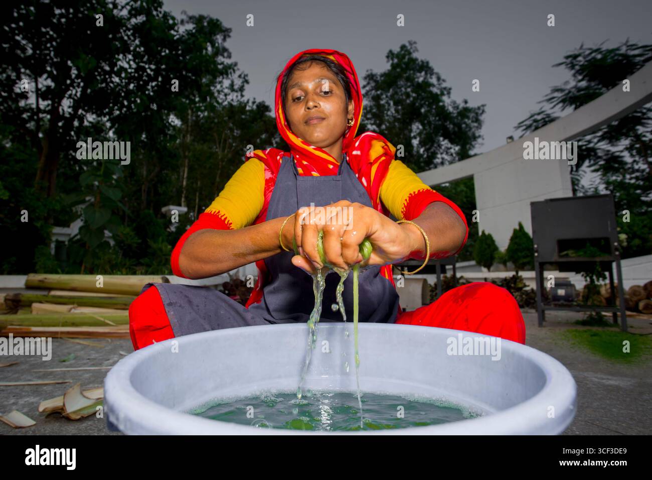 A woman is cleaning on water in hands with manually the green fibers ...