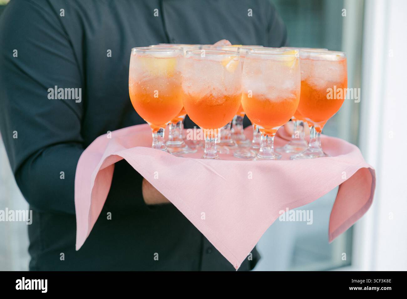 Waiter serves refreshing cocktails on a tray during a summer outdoor ...