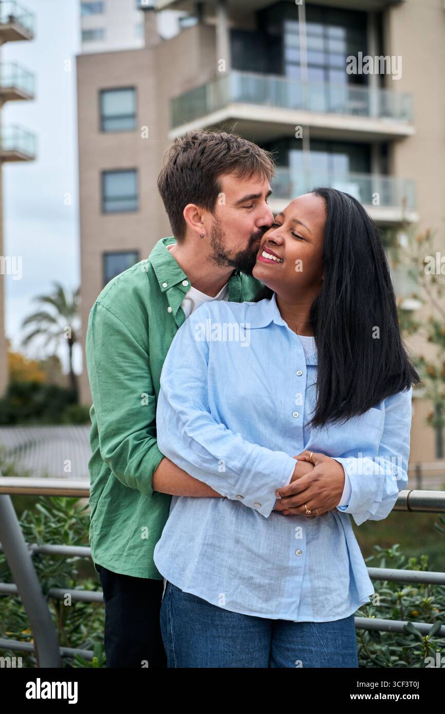 Interracial couple showing affection with a tender kiss on the cheek ...