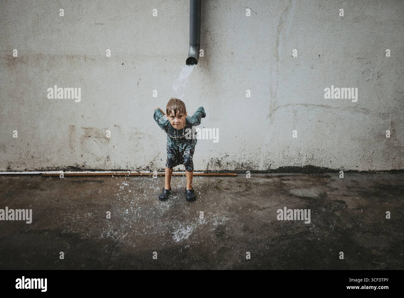 Boy stands under the gutter in the rain in the town of Tarrafal Stock ...