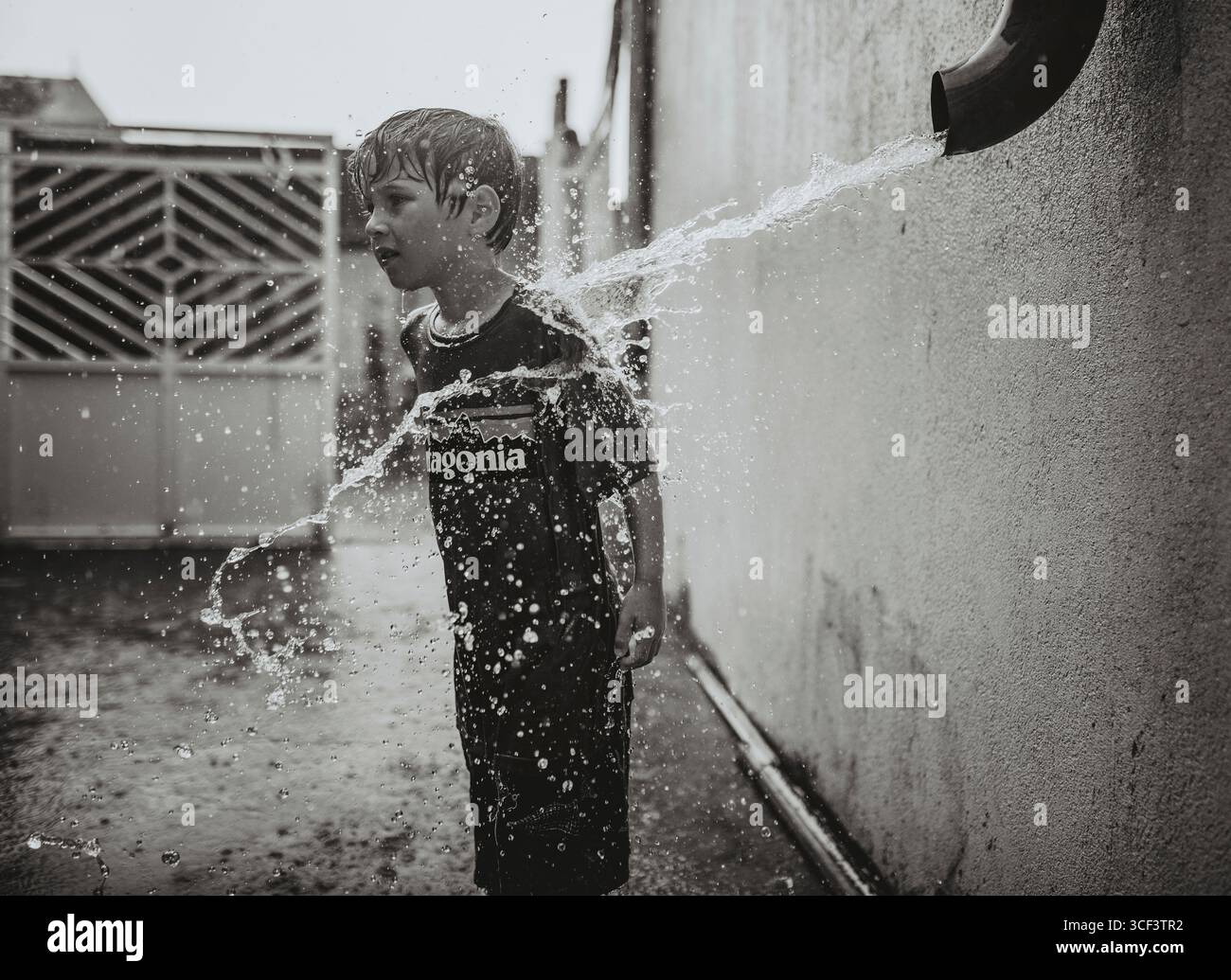 Boy stands under the gutter in the rain in the town of Tarrafal Stock ...