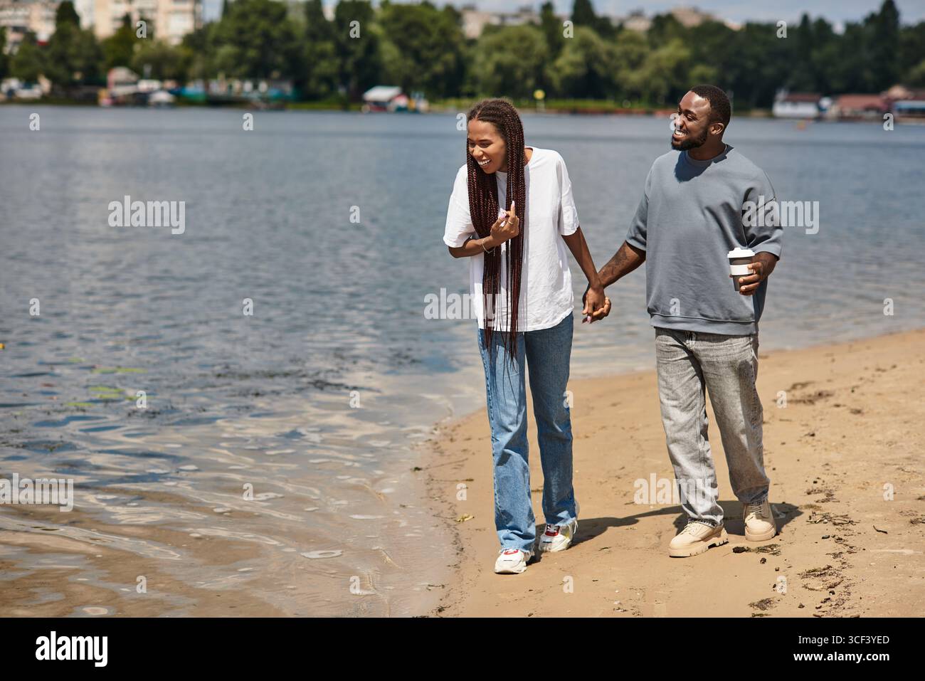 Loving couple walks hand in hand along the sandy lakeside, sharing ...