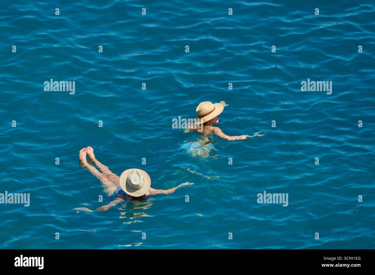 Two Women Relaxing in Bright Blue Water Wearing Straw Hats Stock Photo ...