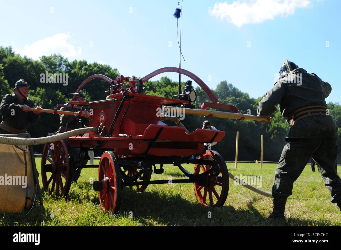 Firefighters using a historic manual hand pump fire engine during ...