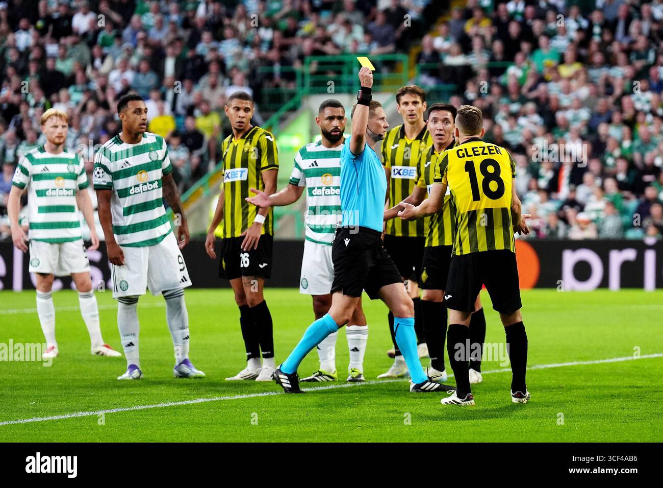 Kairat's Dan Glazer (right) is shown a yellow card by referee Espen ...