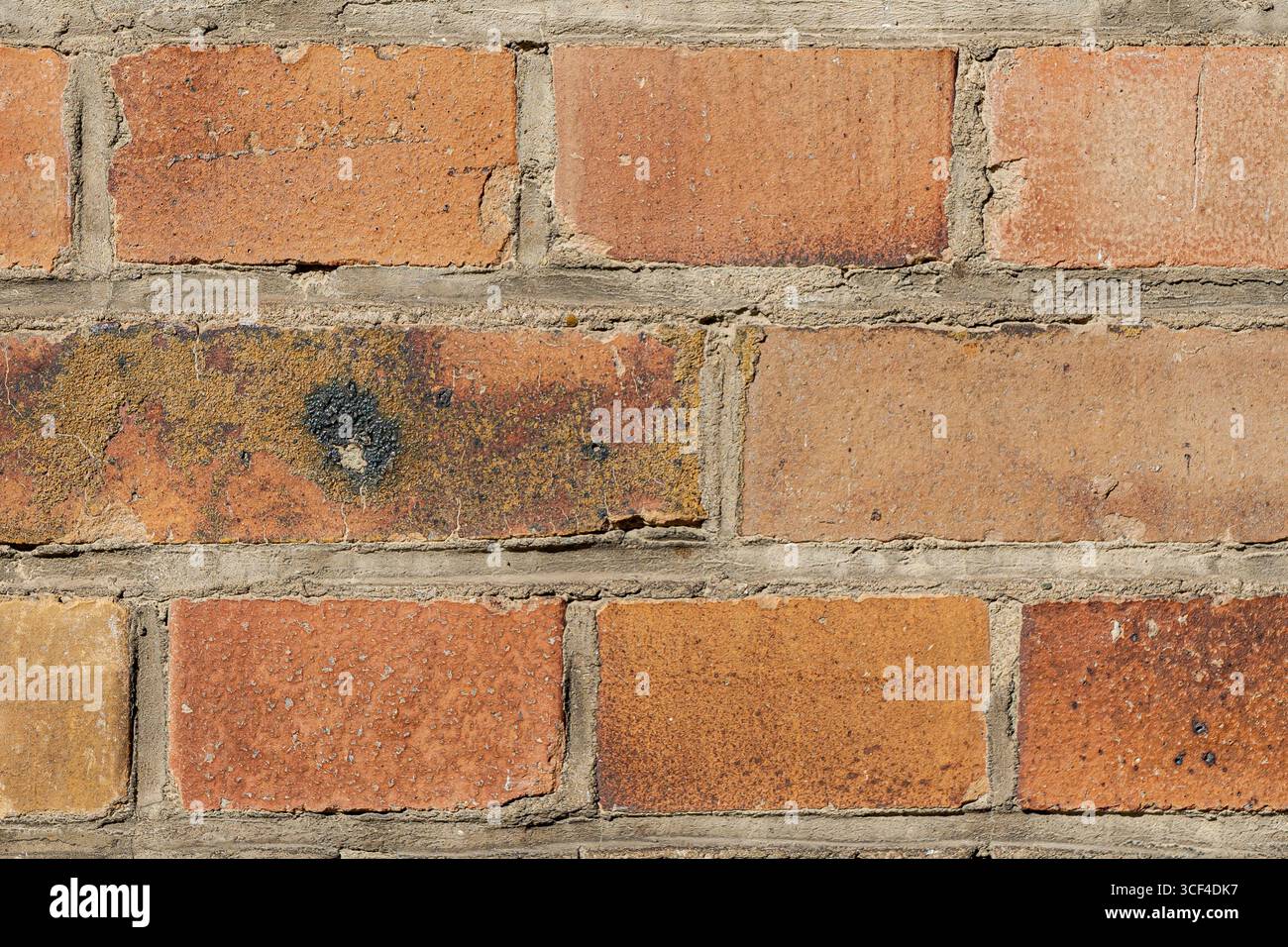 Weathered brick wall, showing warm tones with dark stains and worn ...