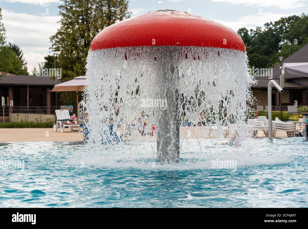 Red mushroom fountain with splashing water in outdoor aqua park pool on ...