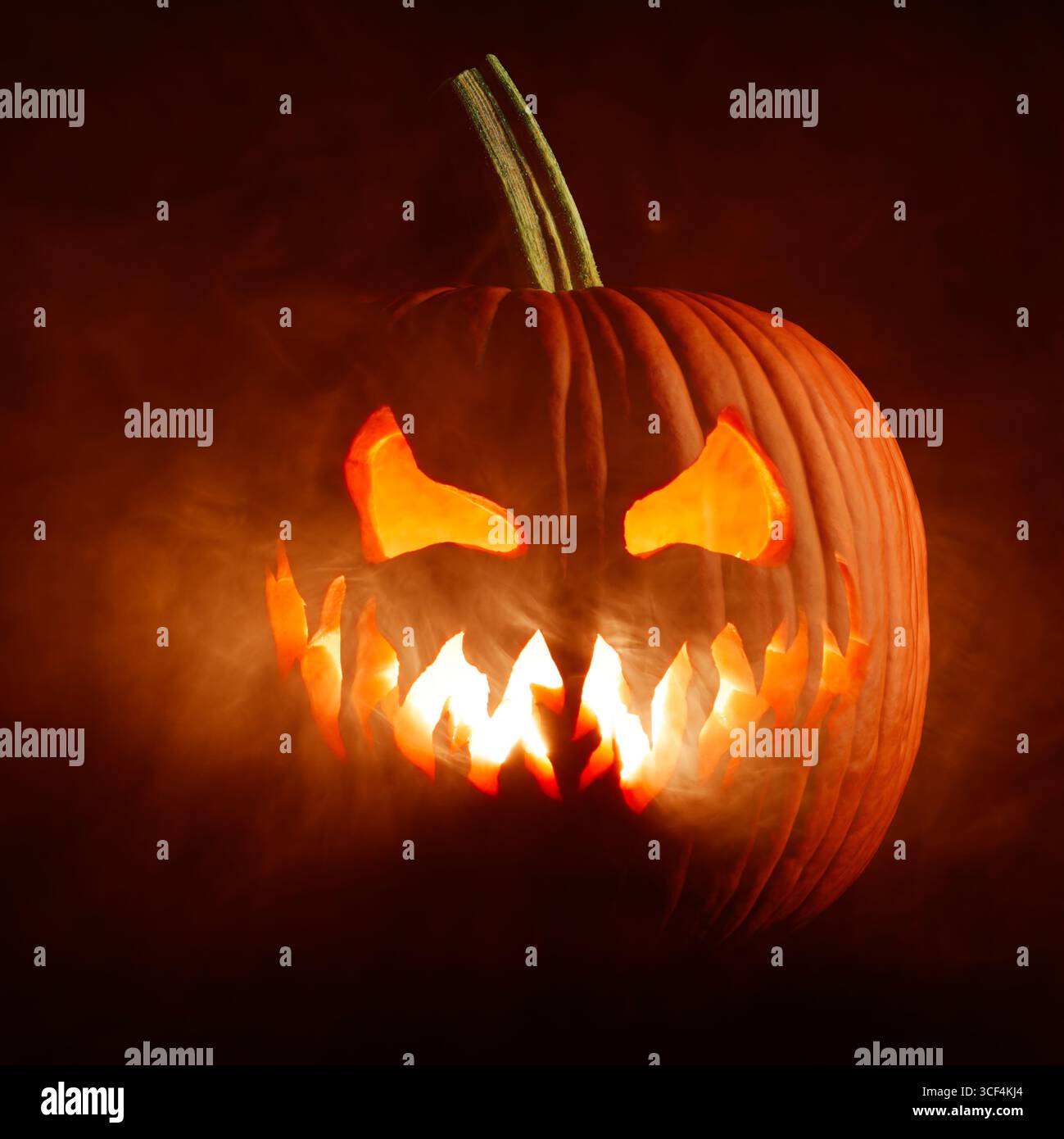 Spooky carved Jack o Lantern glowing a fiery red with thick smoke ...