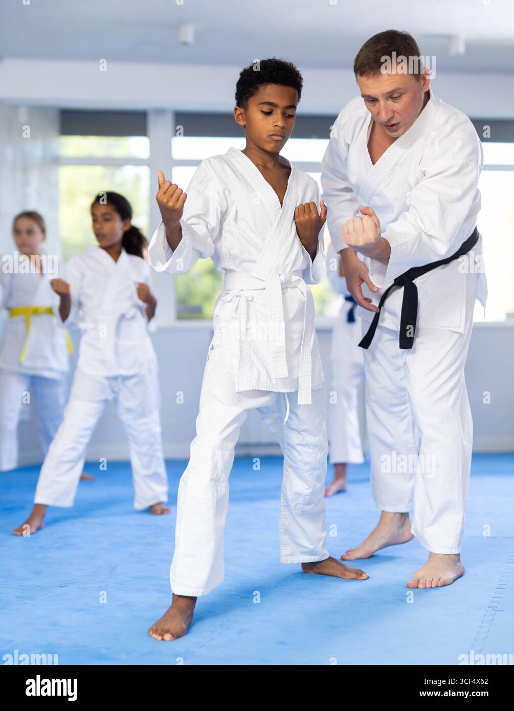 Coach demonstrating punching technique to black boy during karate ...