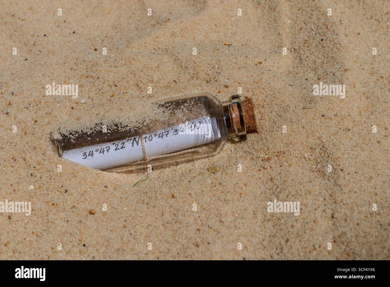 Glass bottle with a rolled-up message showing geographic coordinates ...