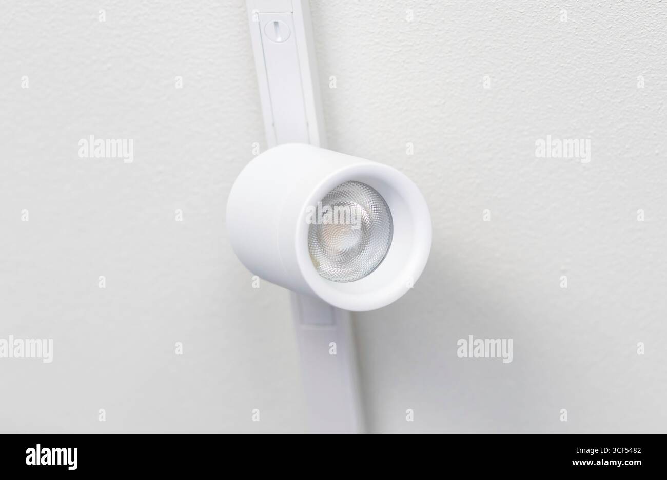 Modern white LED spotlight mounted on a sleek white track lighting ...