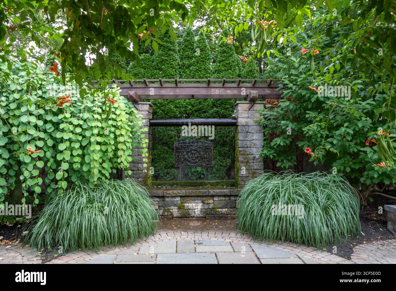 Framed iron waterfall feature with wood pergola and stone pillars ...