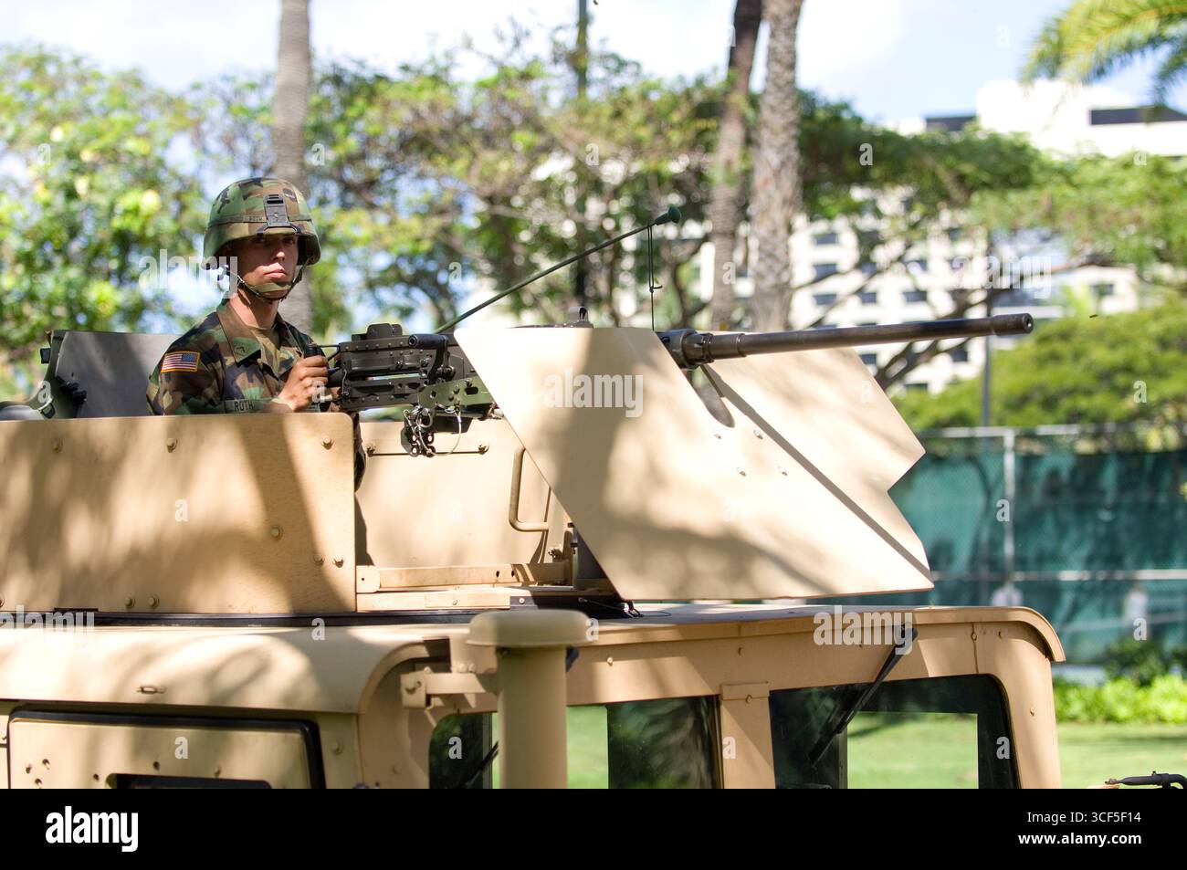 U.S. Army solder manning a 50 caliber machine gun atop an armored HMMWV ...