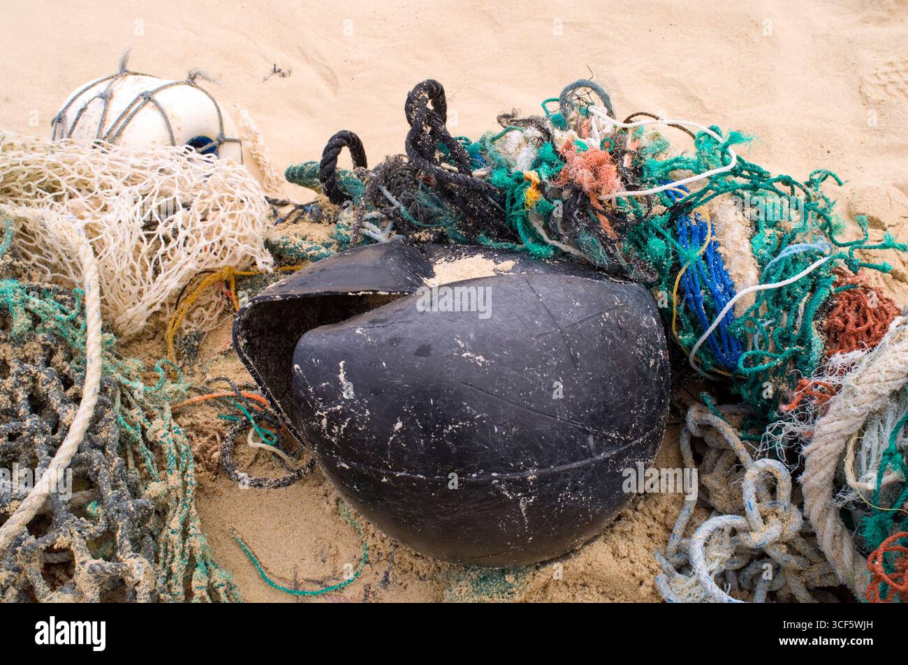 Tangled nets, line, ropes and floats washed ashore on sandy beach ...