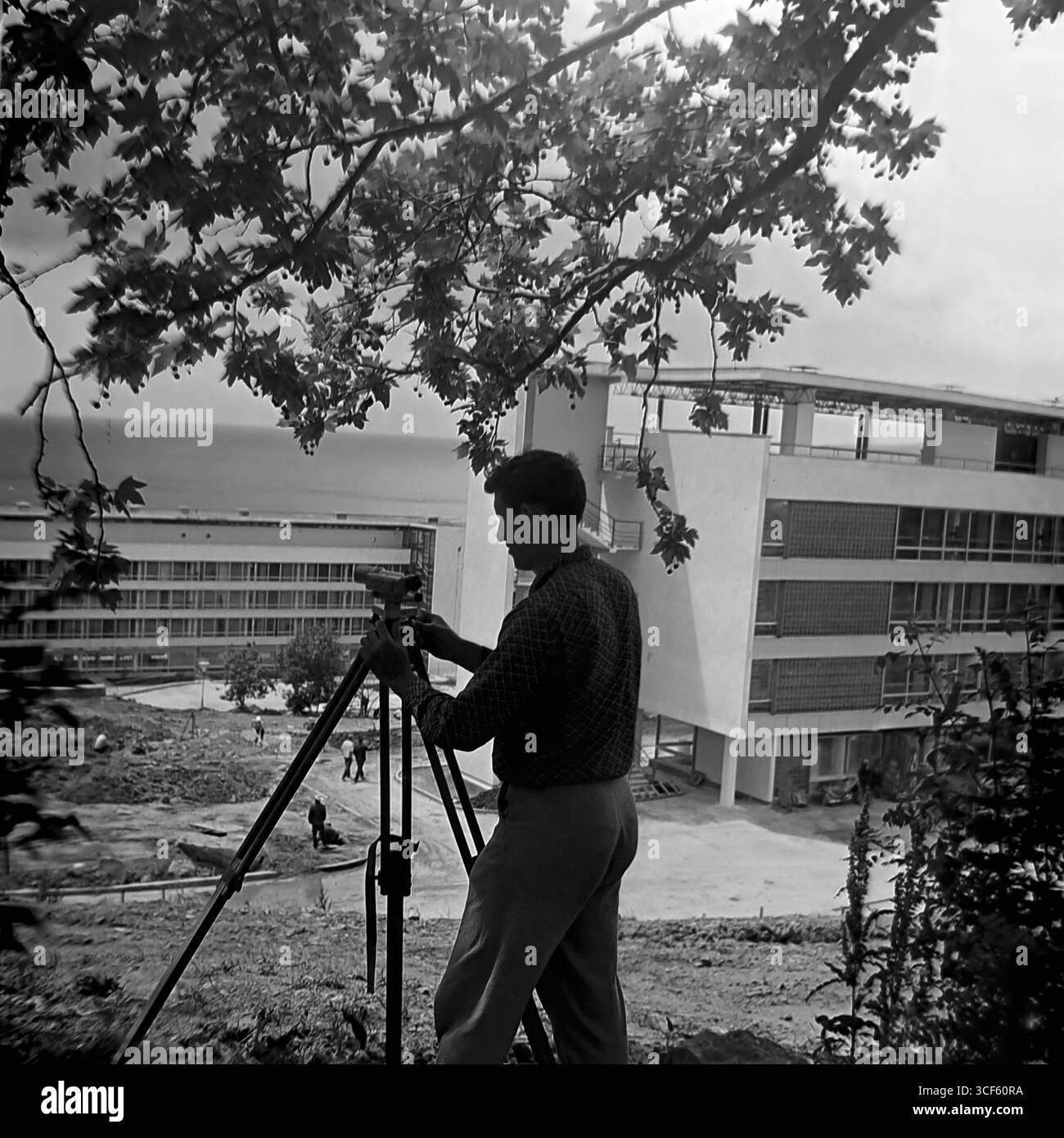 A surveyor engineer with a theodolite against the background of Artek ...