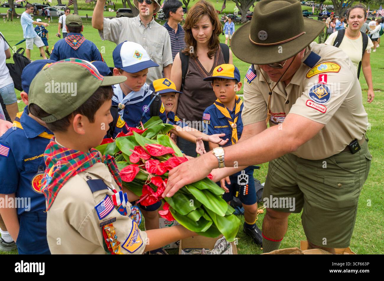 Troop leader handing out bunches of Ti leaves and flowers to Cub Scouts ...