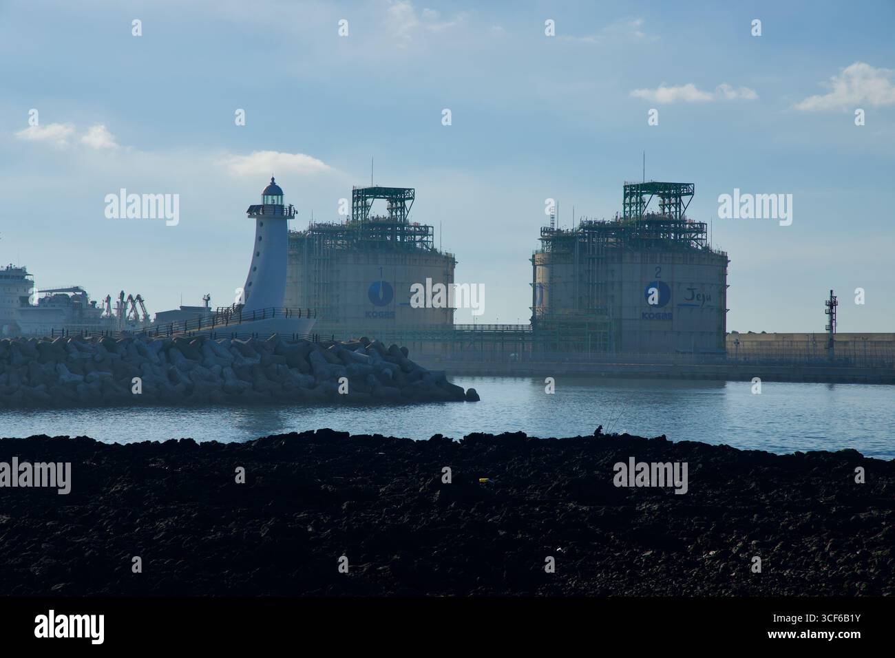 A white lighthouse marks the harbor mouth at Aewol Port, with large ...