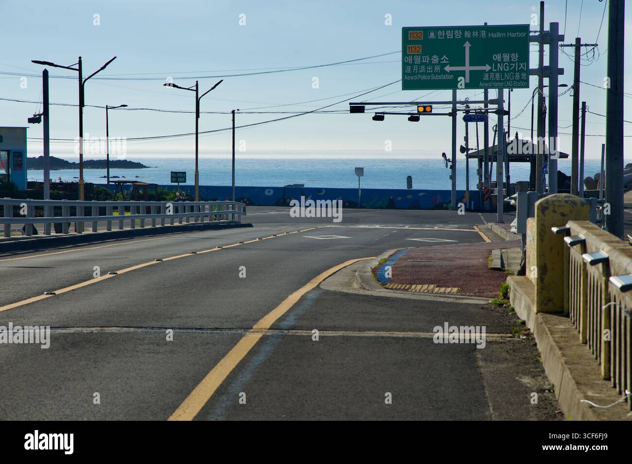 A road junction near Aewol Port faces the sea, with blue mural seawalls ...