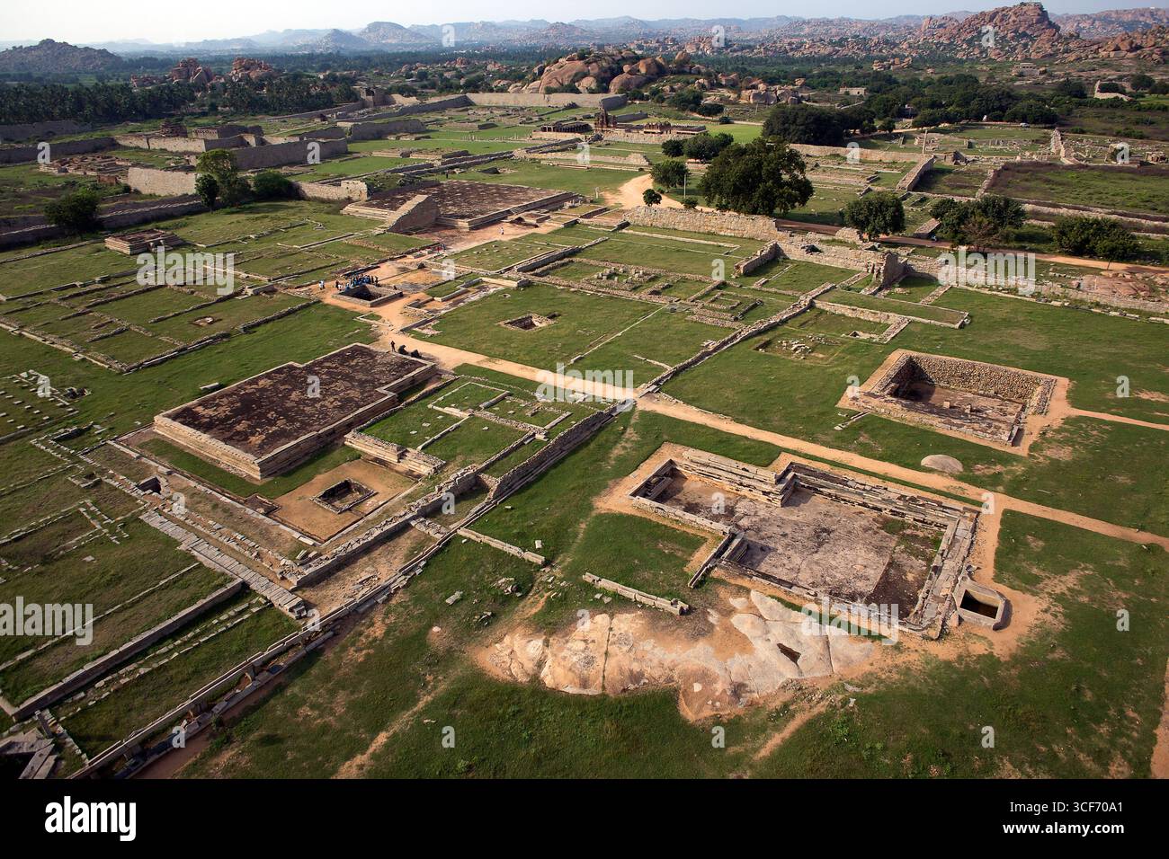 Aerial view of ancient ruins scattered across a vibrant green landscape ...