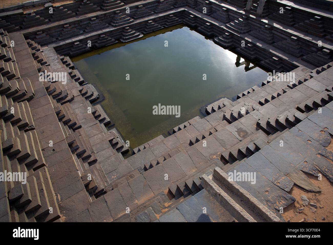 Aerial view of a stepped tank reflecting the sky, with geometric ...