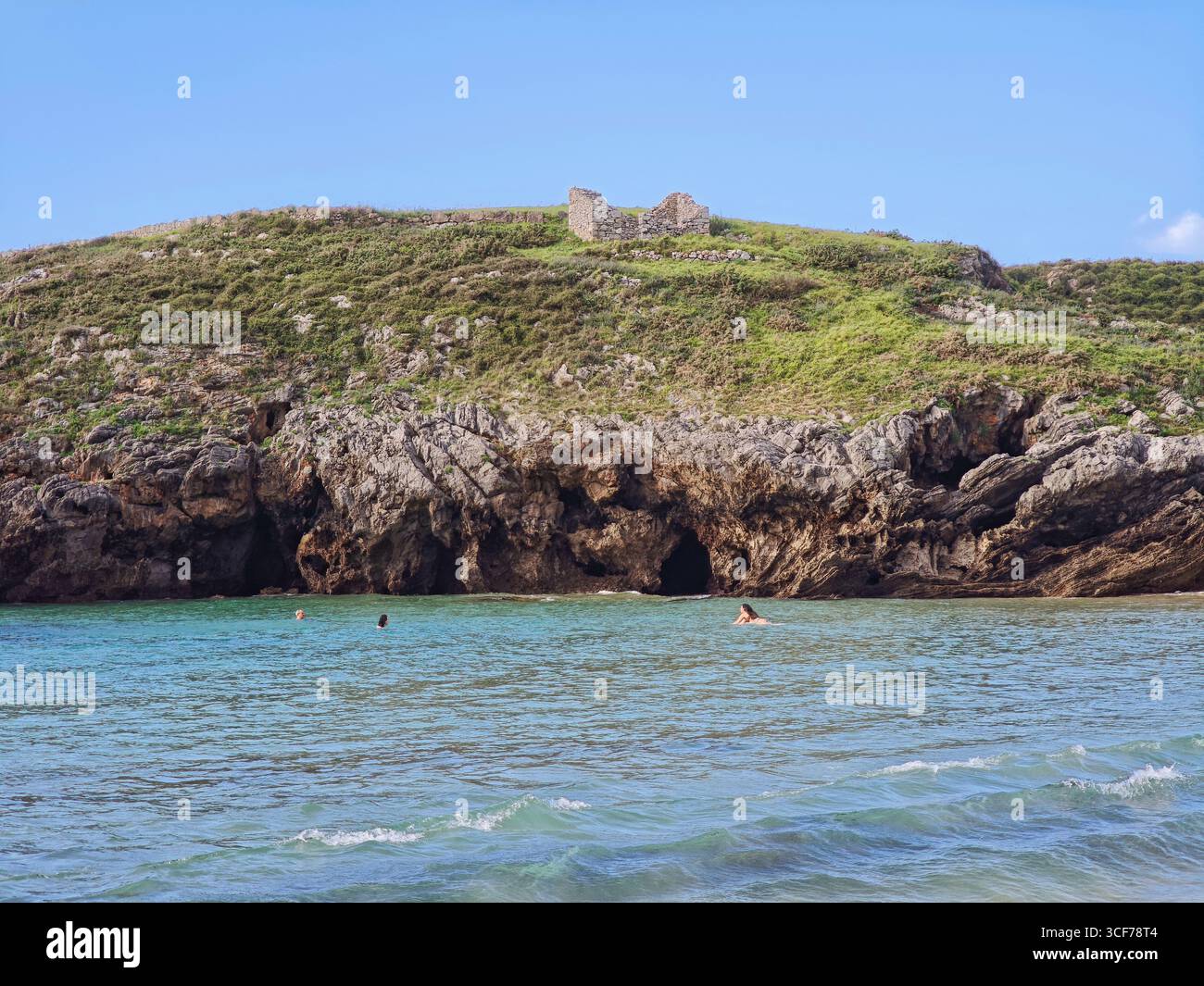 Swimmers drift in the turquoise waters of Cué Beach while the ancient ...