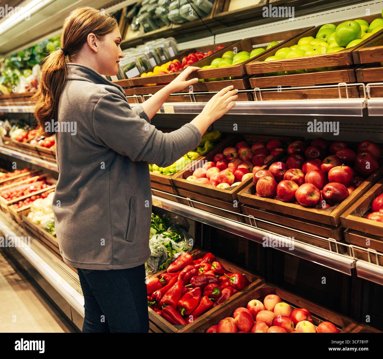 Grocery store employee adjusting shelves with fruits and vegetables ...