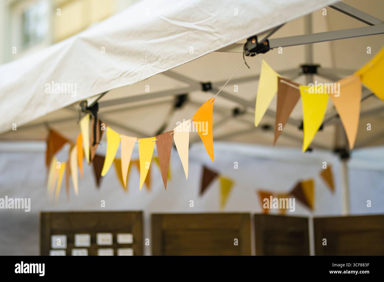 Colorful triangular pennant flags hanging under a white canopy at a ...