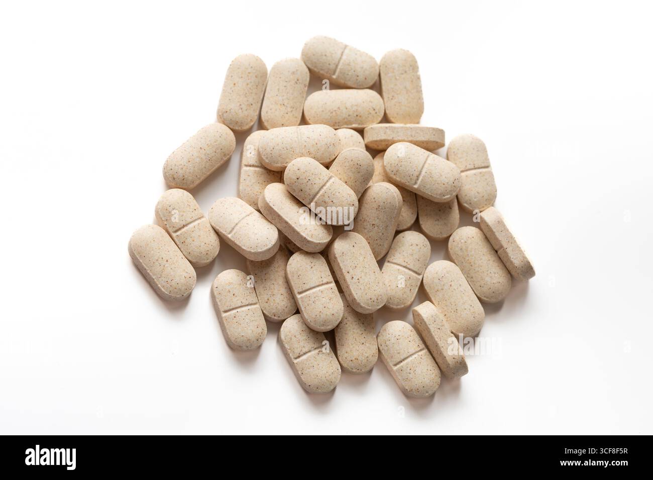 Collection of natural beige supplement capsules with speckled texture ...