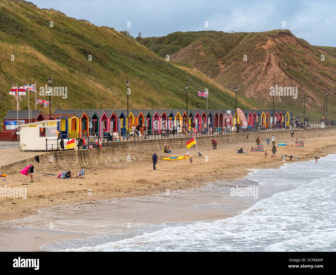 A row of brightly coloured traditional beach huts on the promenade at ...