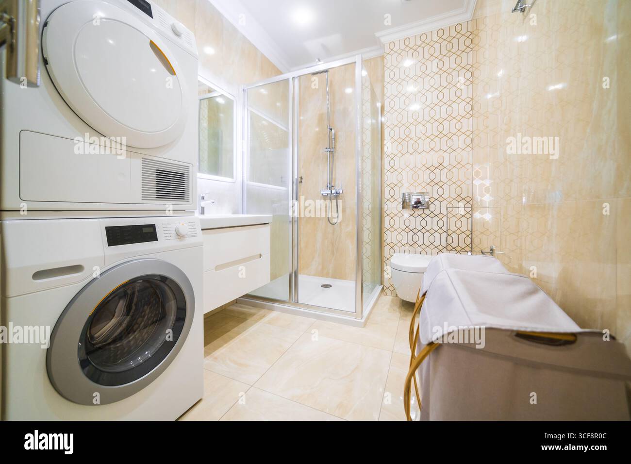 A bathroom with a white washer and dryer, a shower, and a toilet. The ...