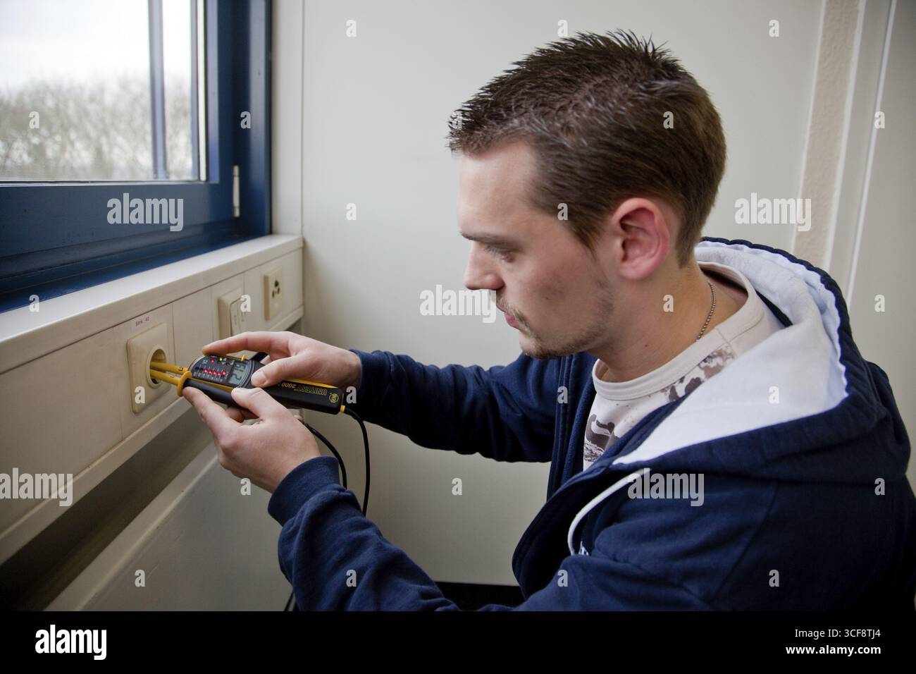 Man using a voltage tester to test a power point Stock Photo - Alamy