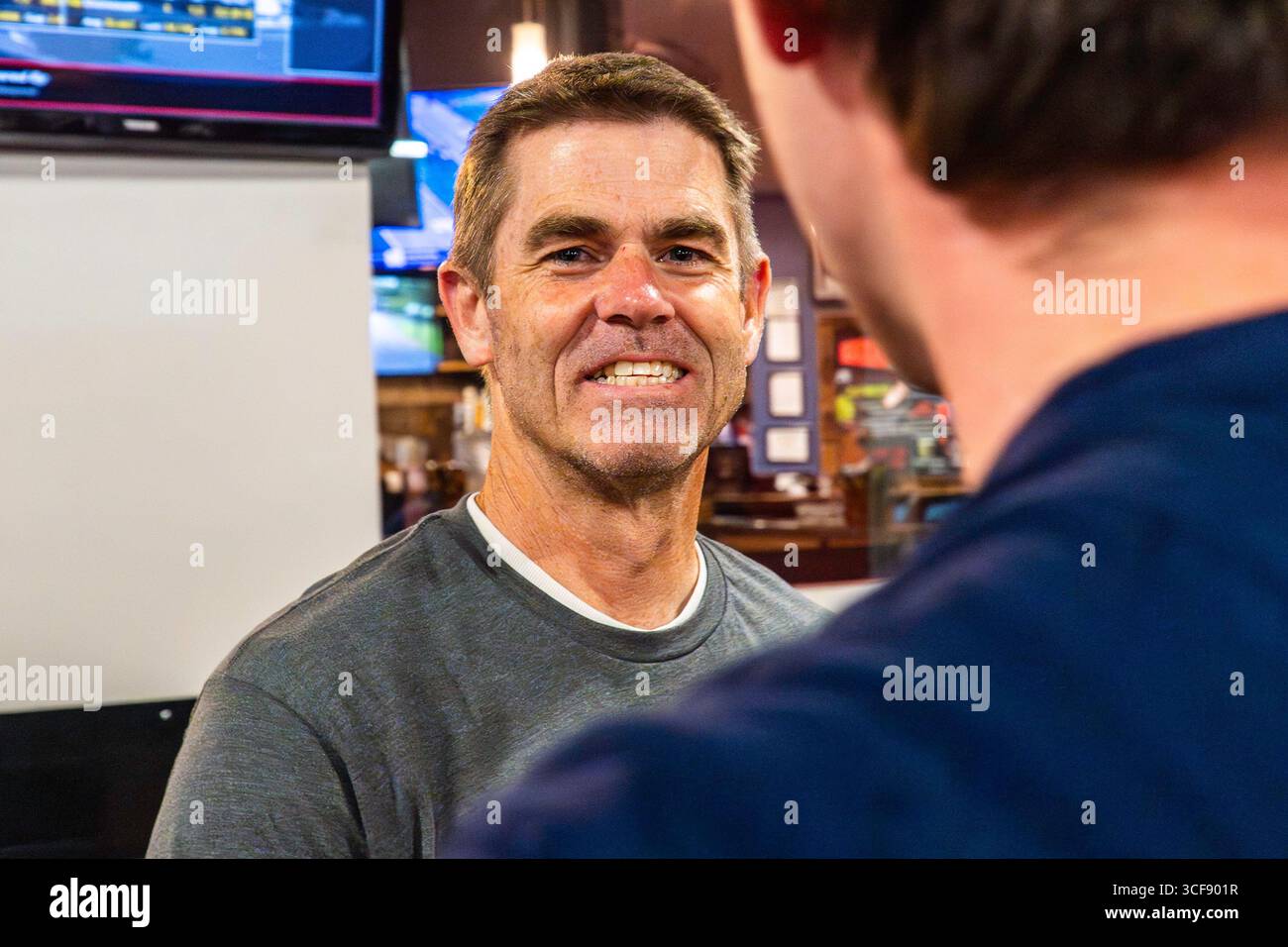 A man smiling while engaging in conversation with another person in a ...