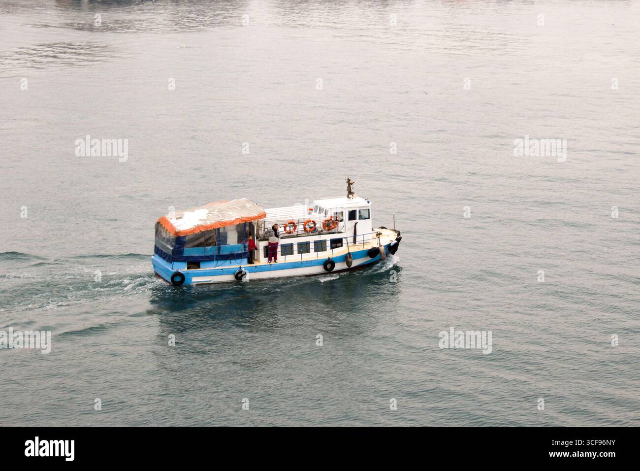 Small passenger boat cruising on calm waters with safety rings from ...