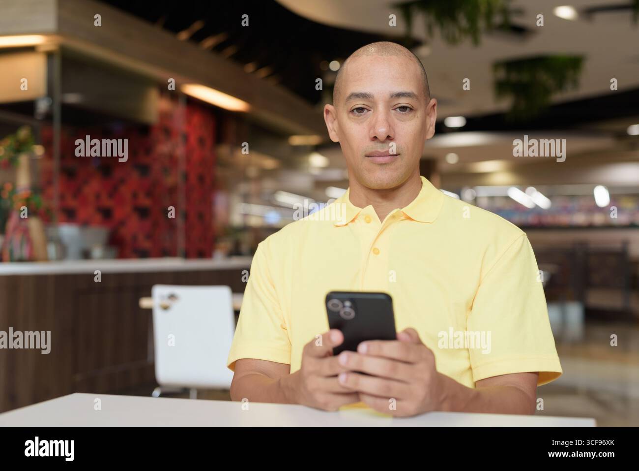 Portrait of a mature bald Italian man sitting indoors at a modern food ...