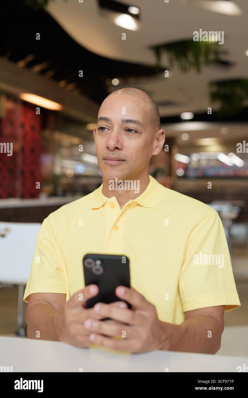 Portrait of a mature bald Italian man sitting indoors at a modern food ...