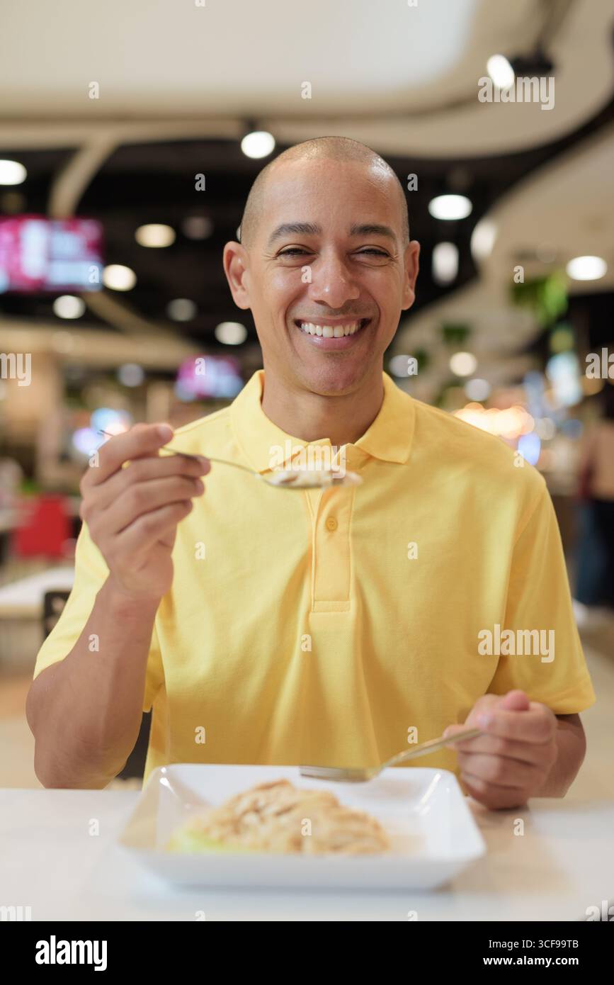 Portrait of a mature bald Italian man sitting indoors at a modern food ...