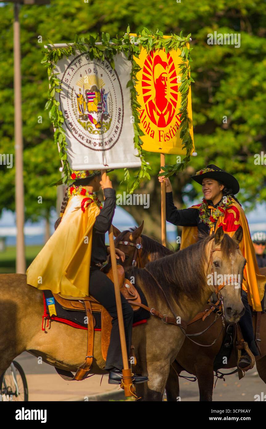 Male paniolo riders on horseback holding banners before the start of ...