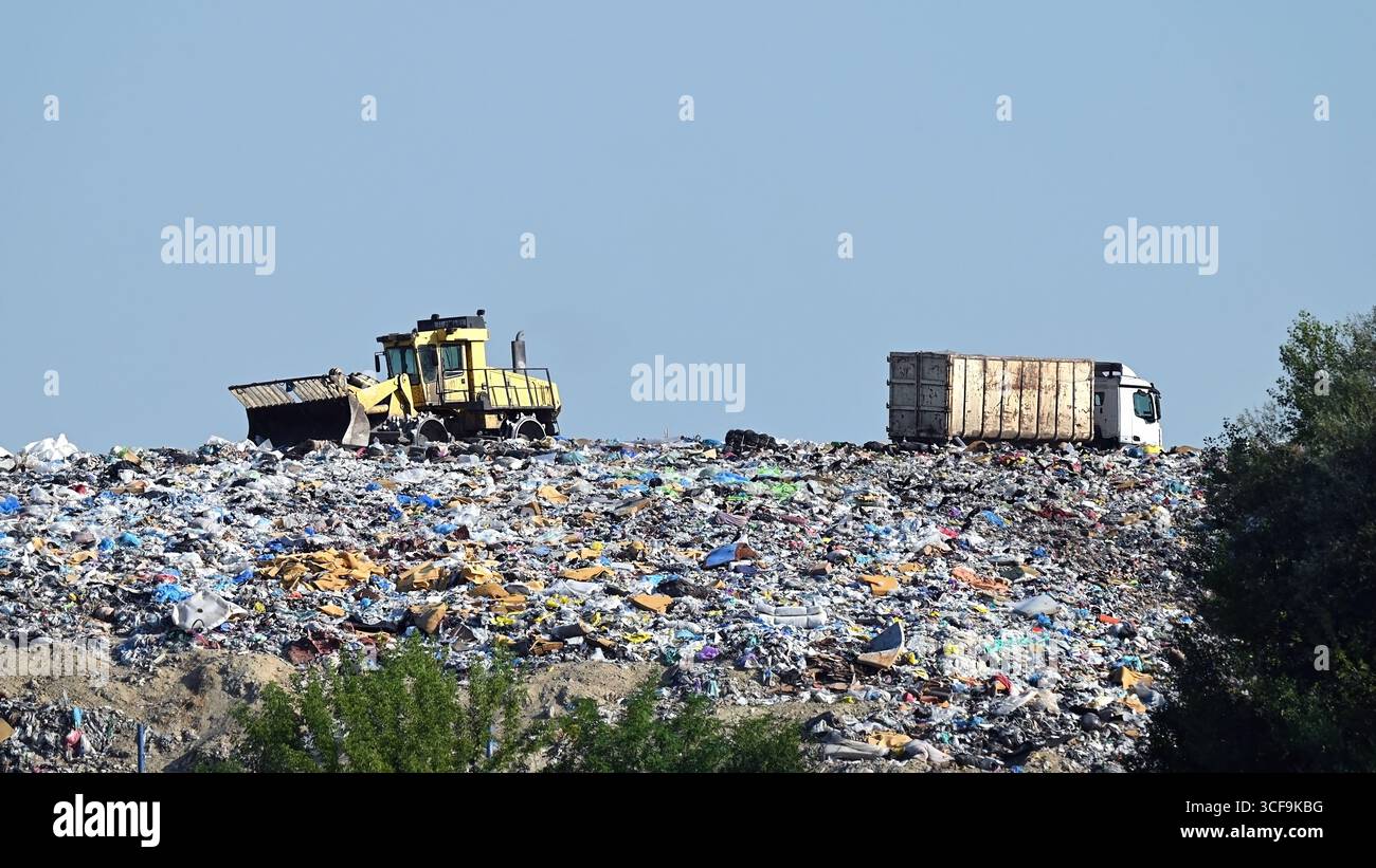 Industrial compactor and rubbish lorry operating on a pile of waste in ...
