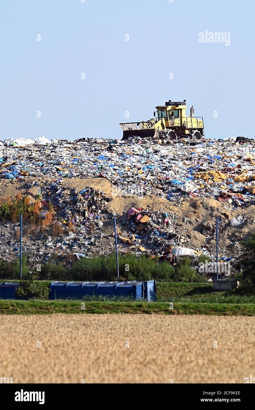 Industrial compactor operating on a pile of waste in a landfill site ...