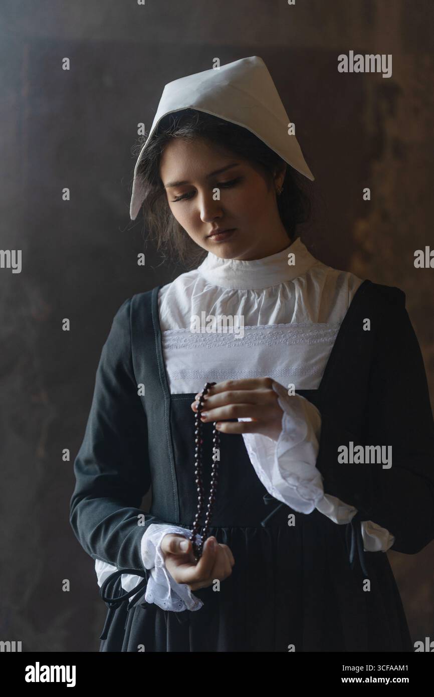 Serene nun in traditional wimple holding rosary within historic ...
