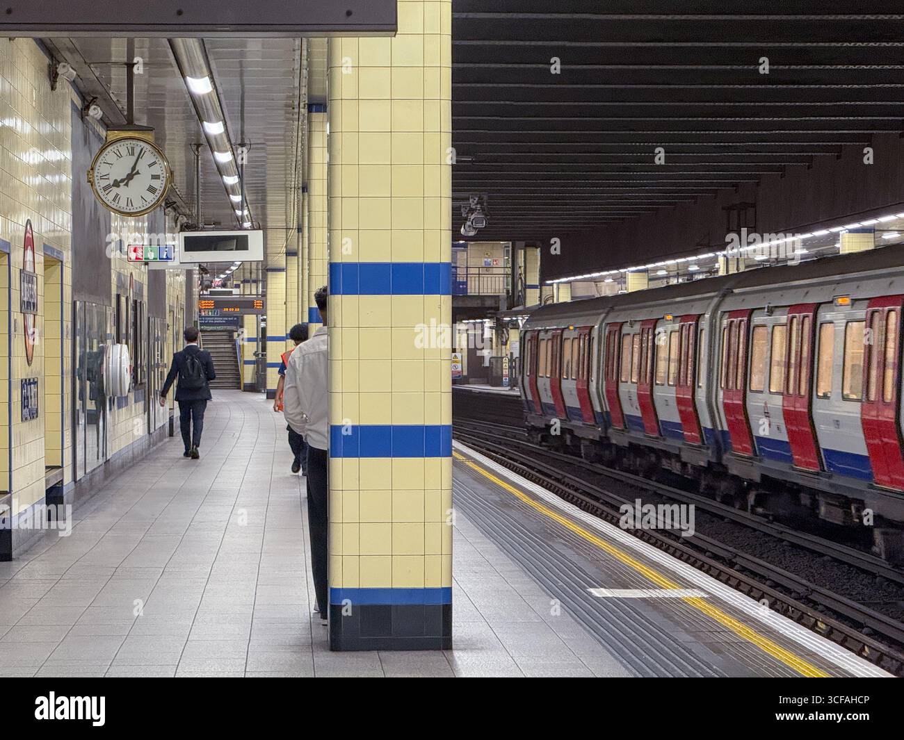 passengers waiting on London Underground Platform with Yellow-Tiled ...